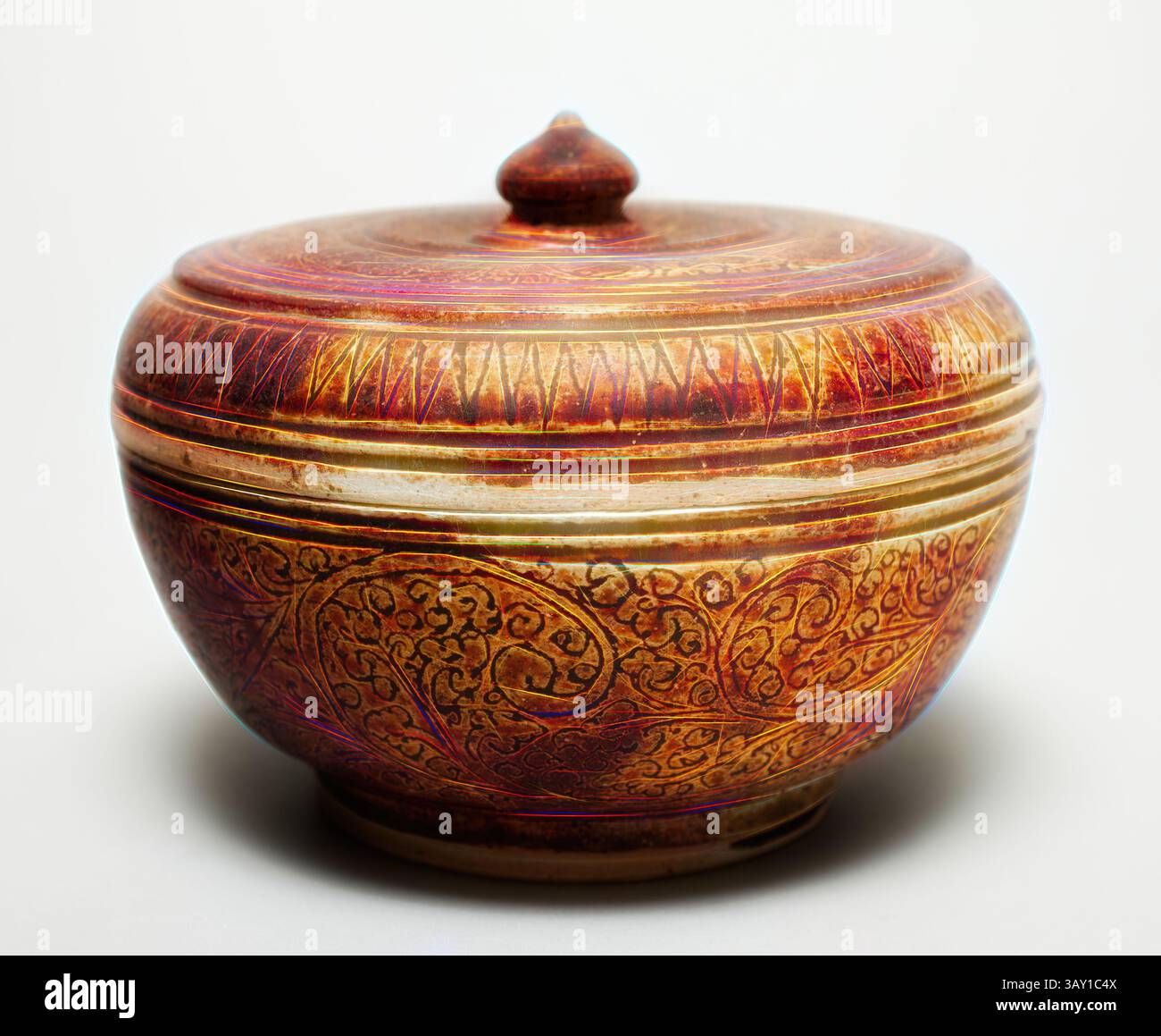 An ornate, round container featuring intricate engravings and a ...