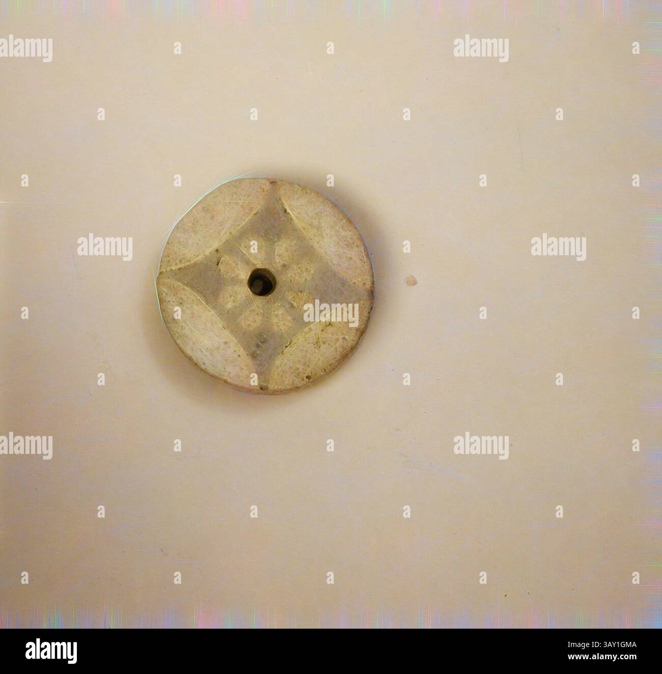 A round, textured object featuring a geometric design with a central ...