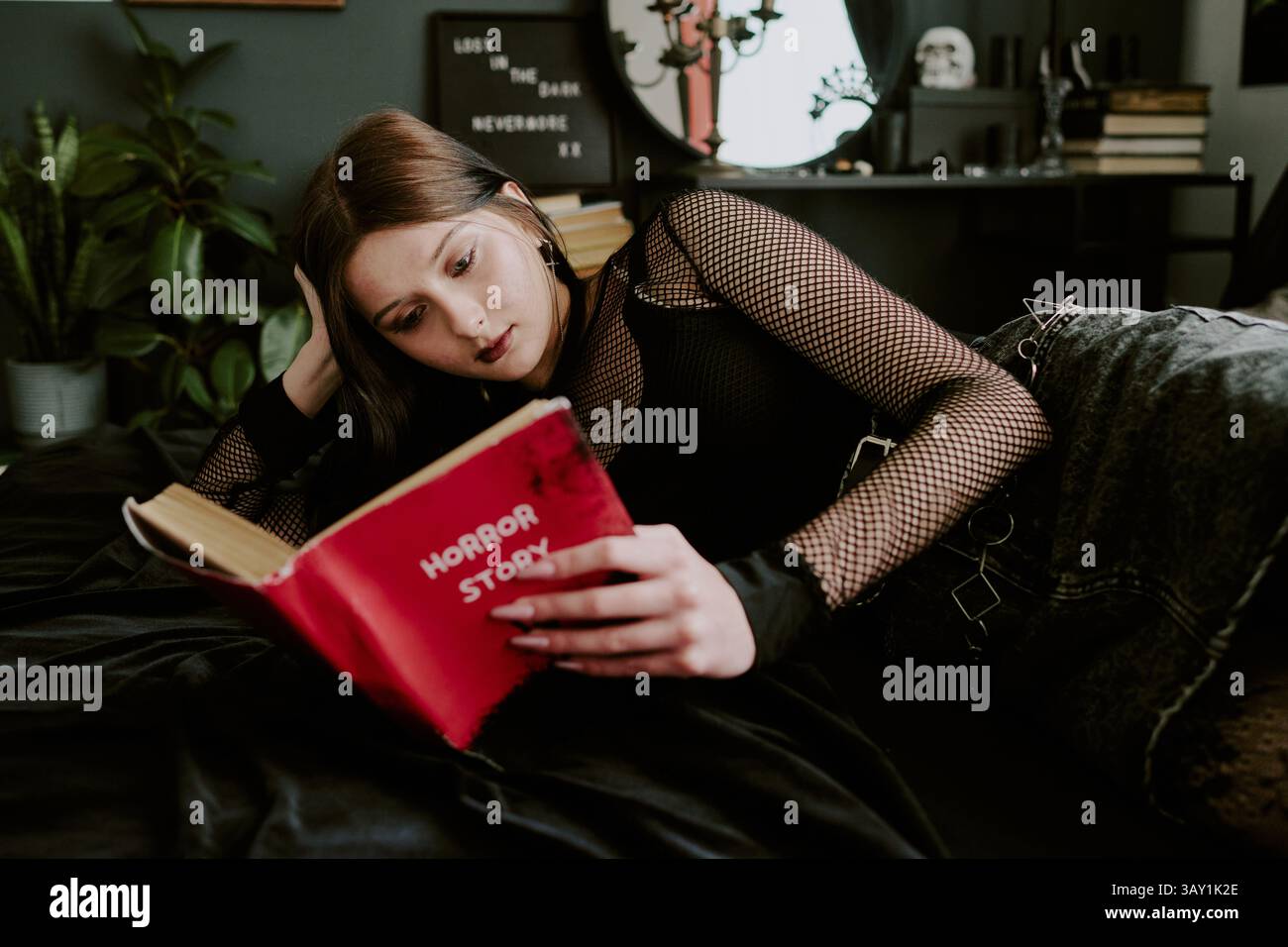 Medium shot of beautiful teen girl enjoying reading horror story while ...