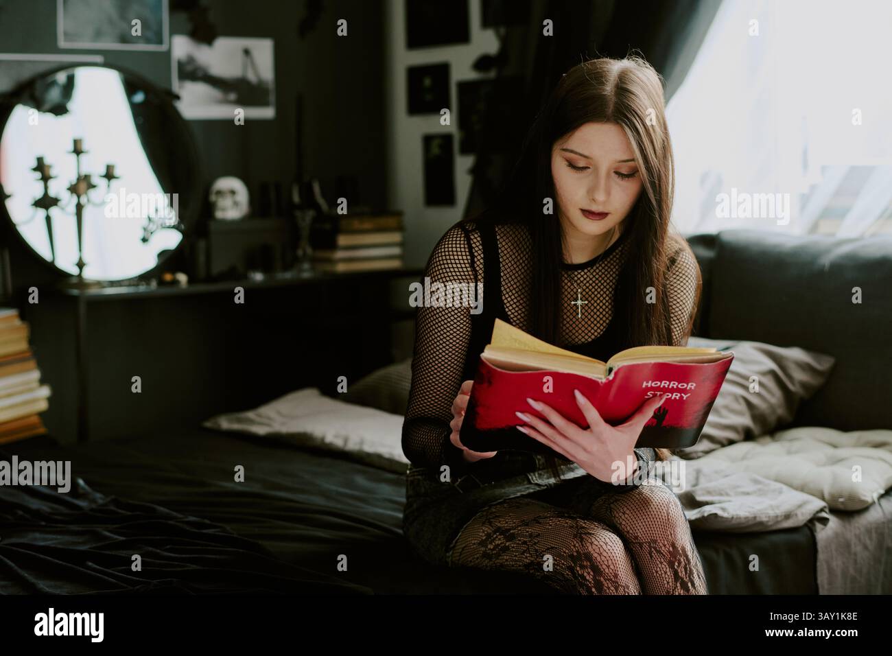 Medium shot of brilliant goth teen girl sitting on bed and enjoying ...