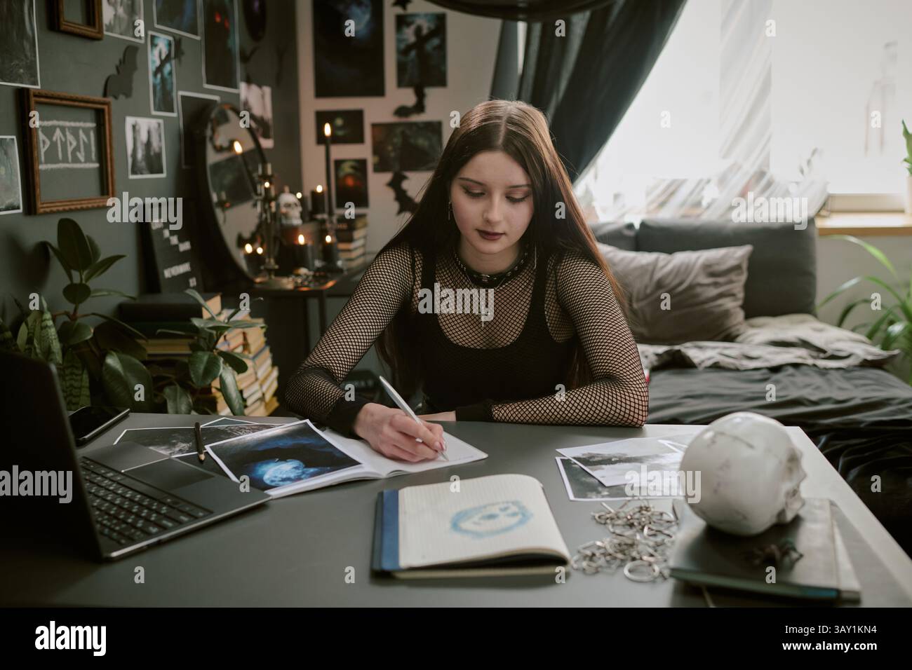 Medium shot of brilliant goth teen girl in total black sitting at table ...