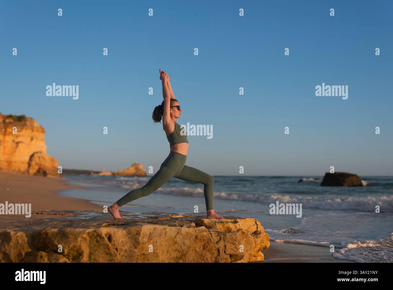 sporty woman practicing yoga by the sea doing a high lunge pose Stock ...
