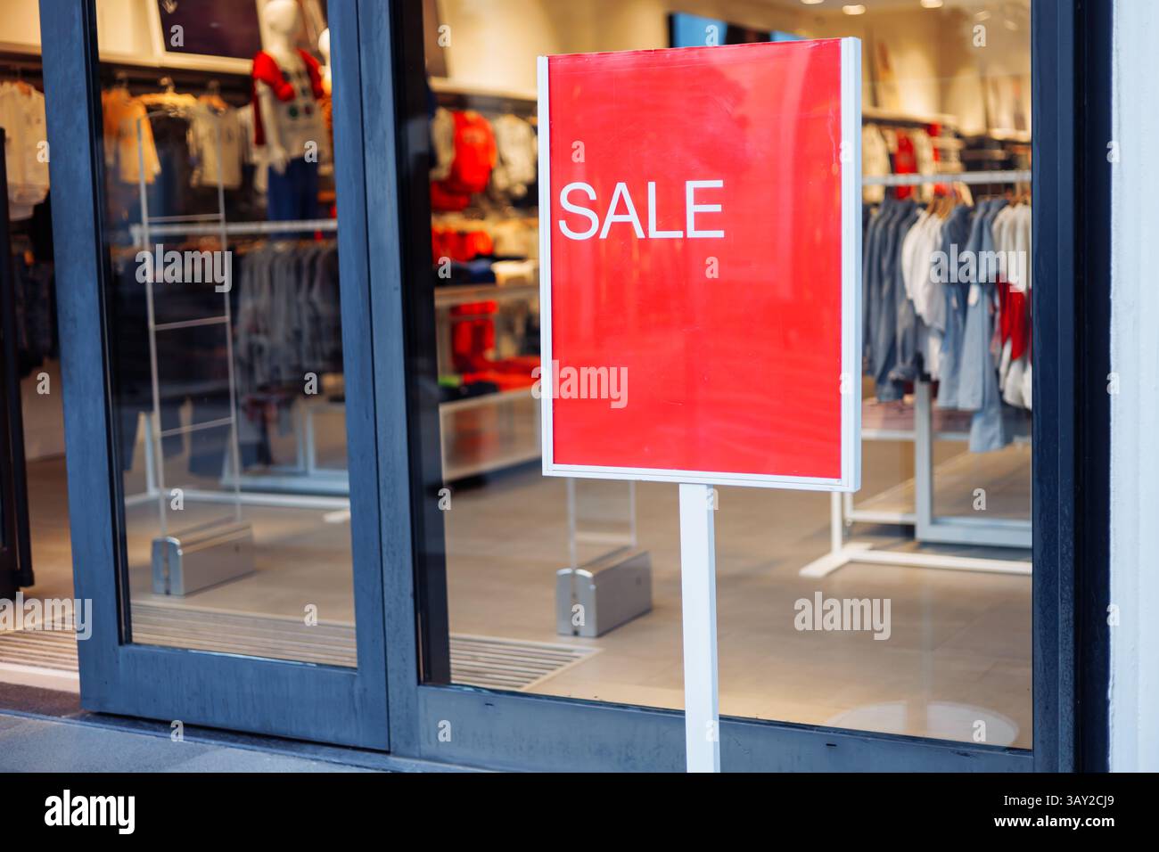 Bright red mockup sale sign stands prominently outside a clothing store ...