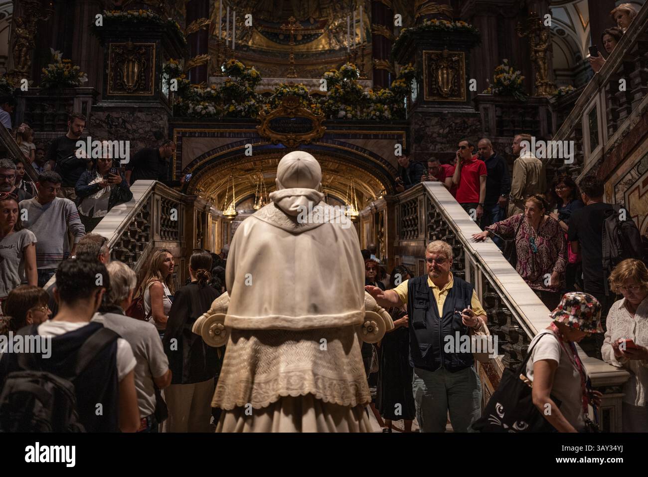 Rome, Italy. 22nd Apr, 2025. Pilgrims walk past the marble statue of ...