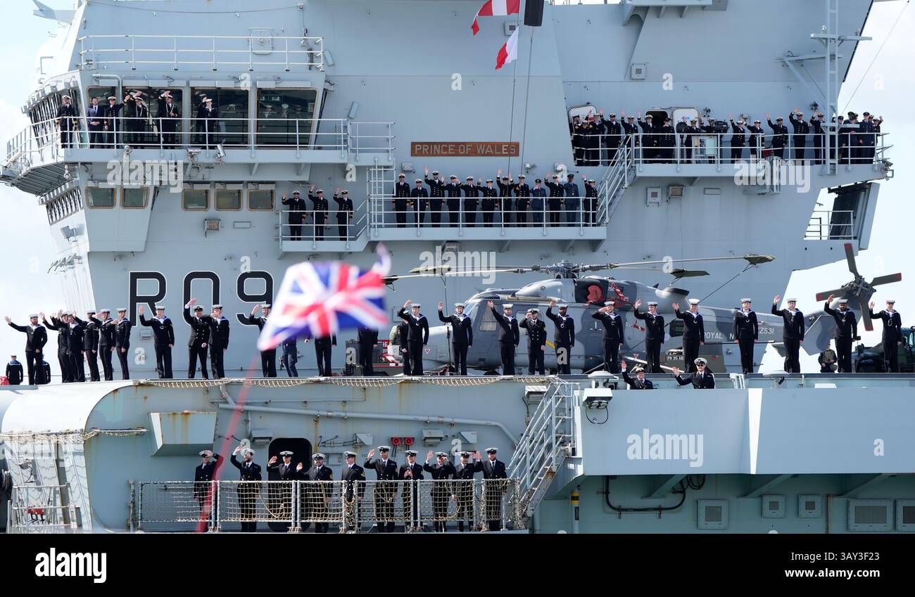 Royal Navy personnel wave from the side of the Royal Navy aircraft ...
