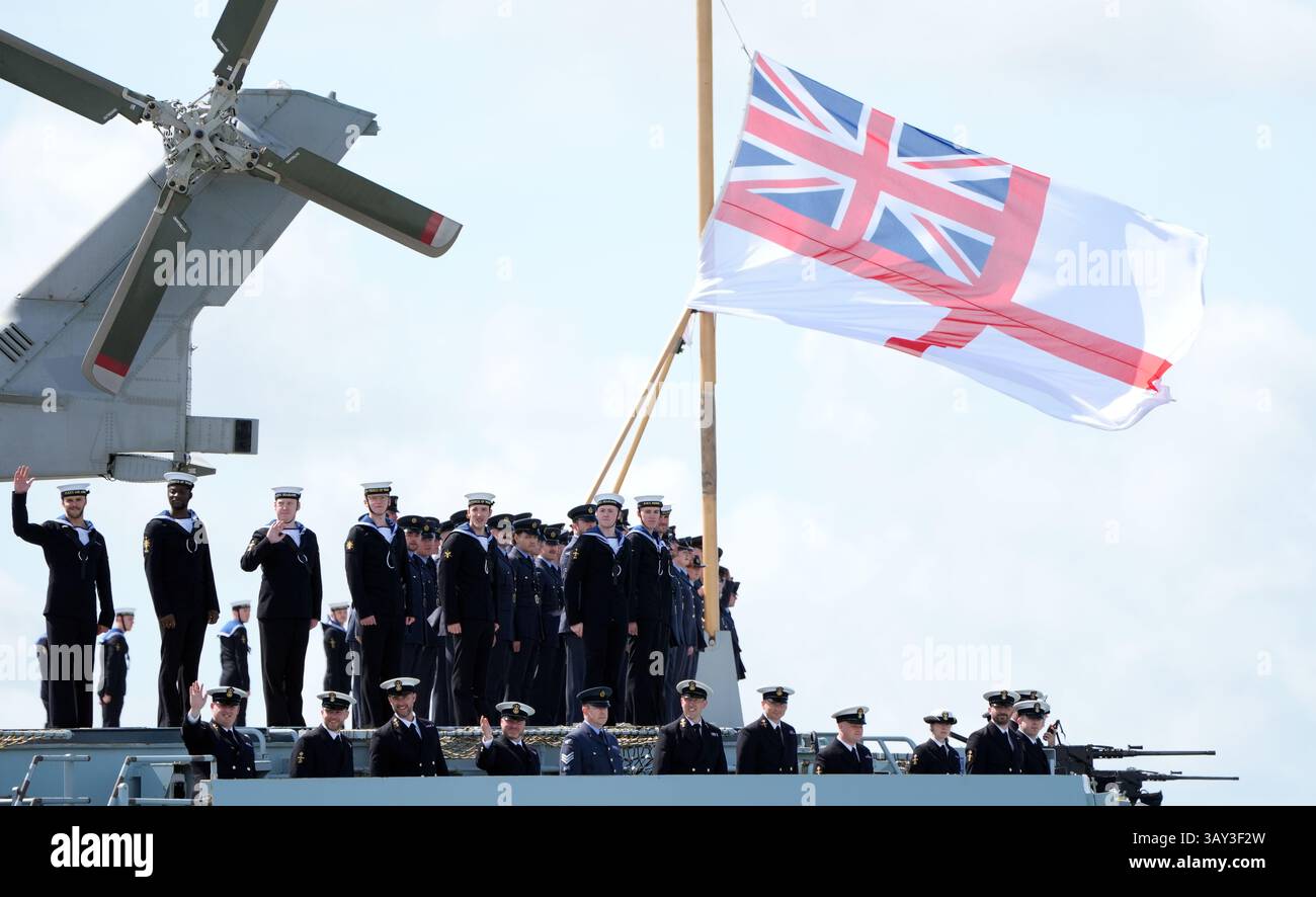 Royal Navy personnel line the stern of the Royal Navy aircraft carrier ...