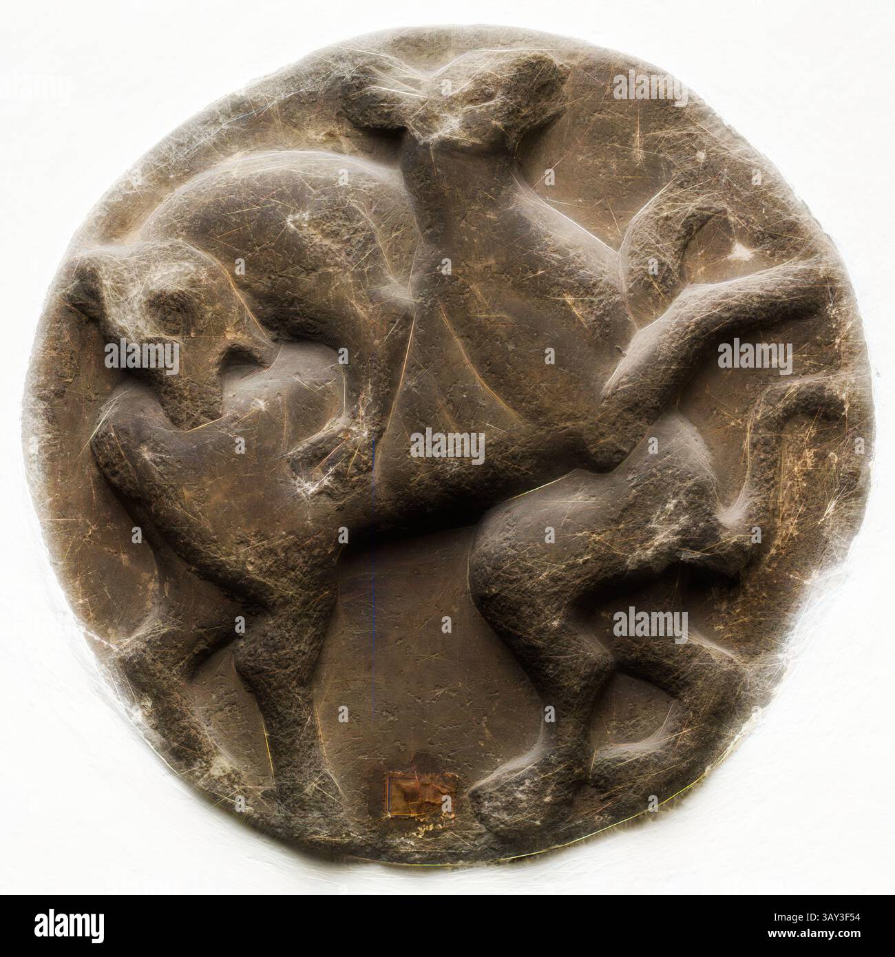 A circular relief depicts two animals engaged in a dynamic interaction ...