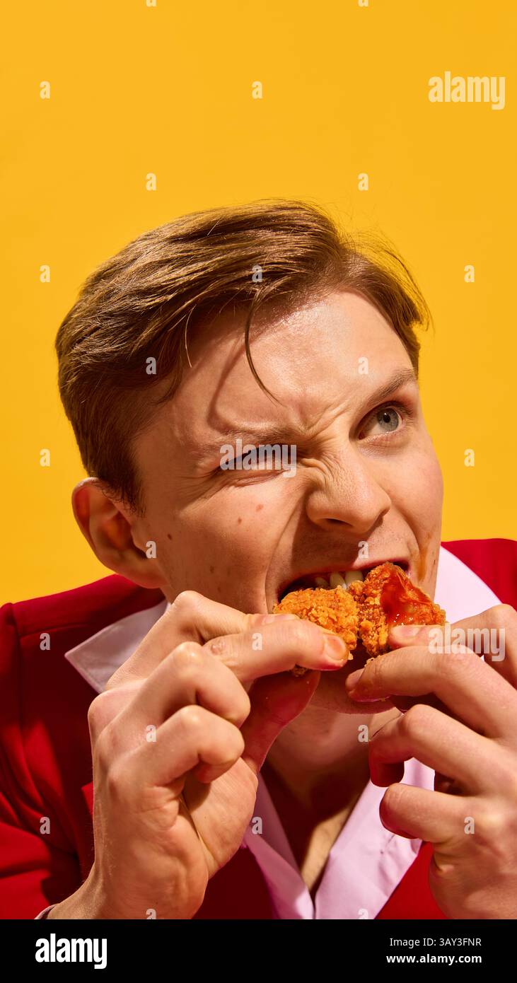 Close-up portrait of man emotionally biting crispy chicken wing with ...