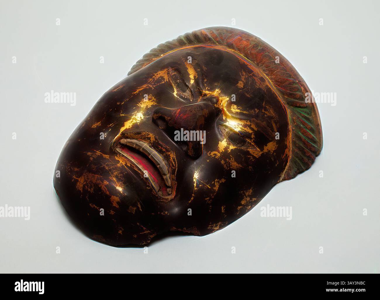 A detailed mask carved from a dark, shiny material, featuring an ...