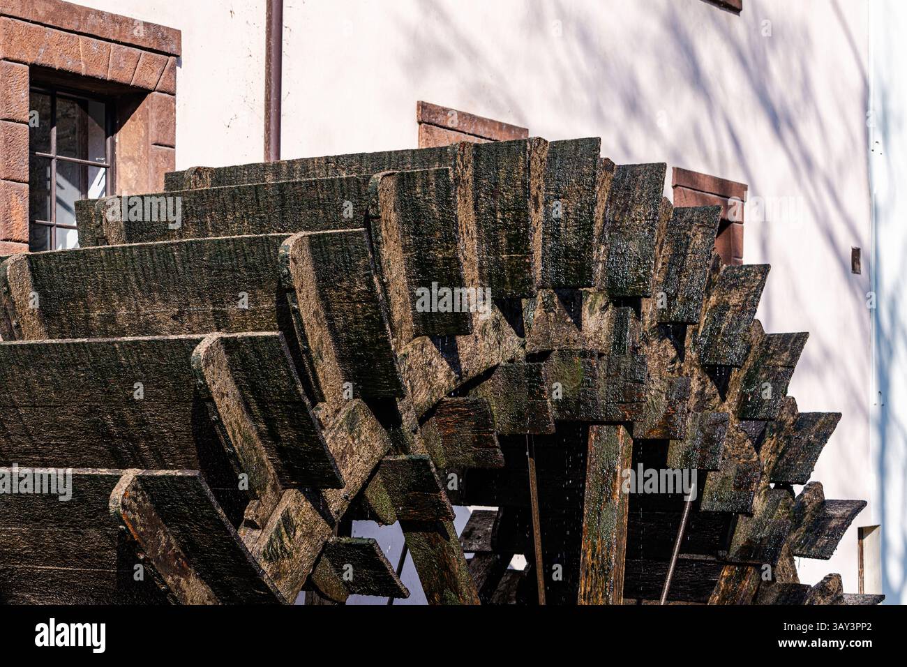 A close-up of a traditional wooden waterwheel against a historic Prague ...