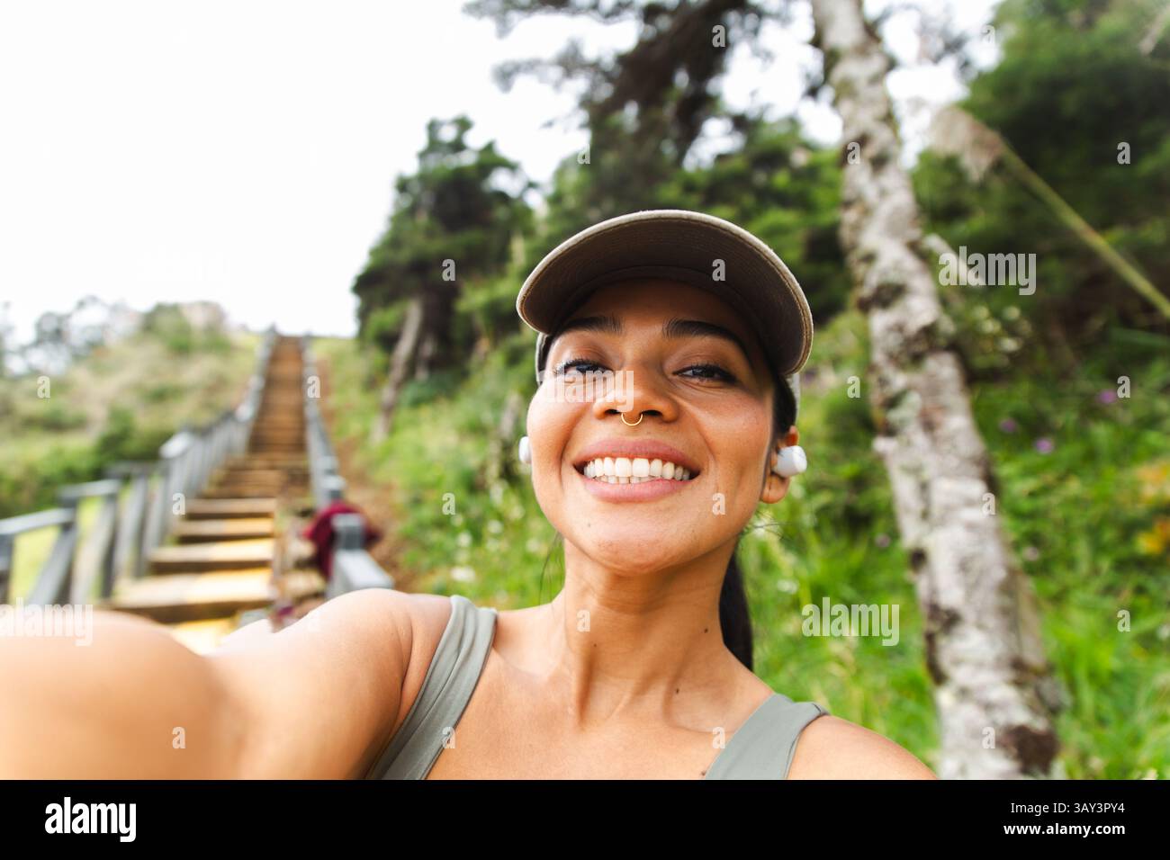 An Ecuadorian woman takes a cheerful selfie on a forest stair trail in Loja, Ecuador. Wearing a ...