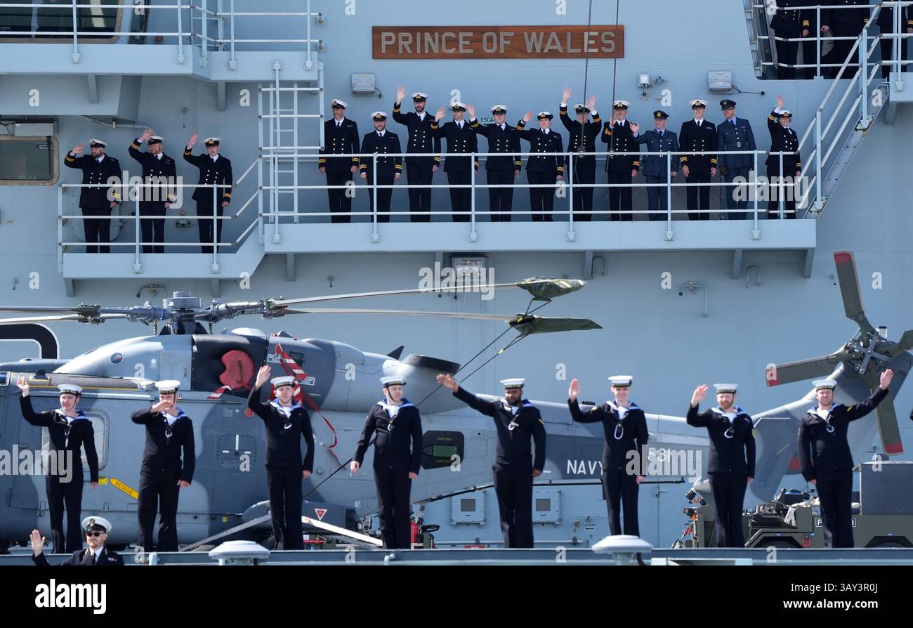 Royal Navy personnel wave from the side of the Royal Navy aircraft ...