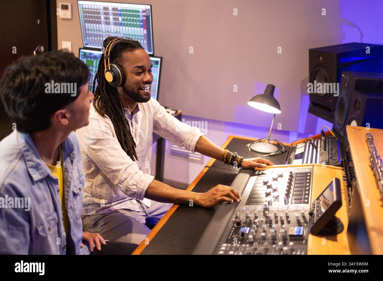 Two sound engineers collaborate in a recording studio, using audio equipment and computer ...