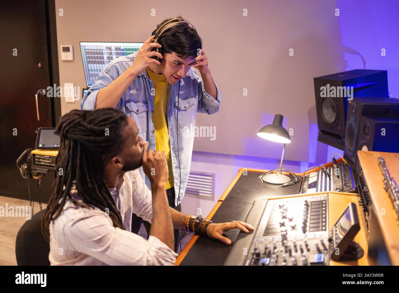 Two men collaborate in a professional recording studio, surrounded by ...