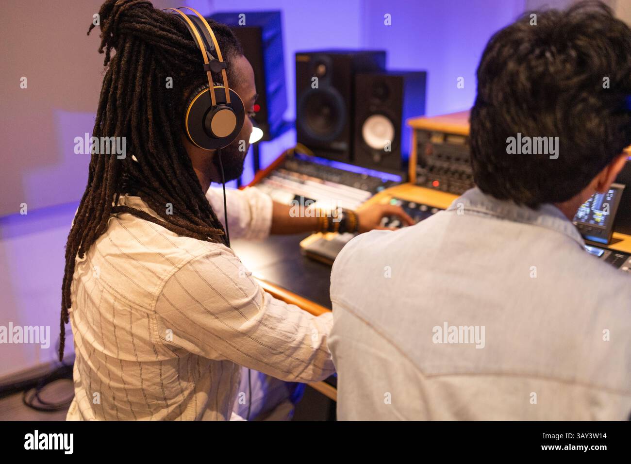 The musicians work together in a modern recording studio. They focus on ...