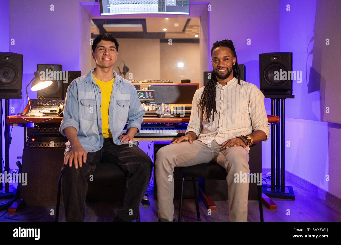 Two musicians seated in a professional recording studio. The room ...