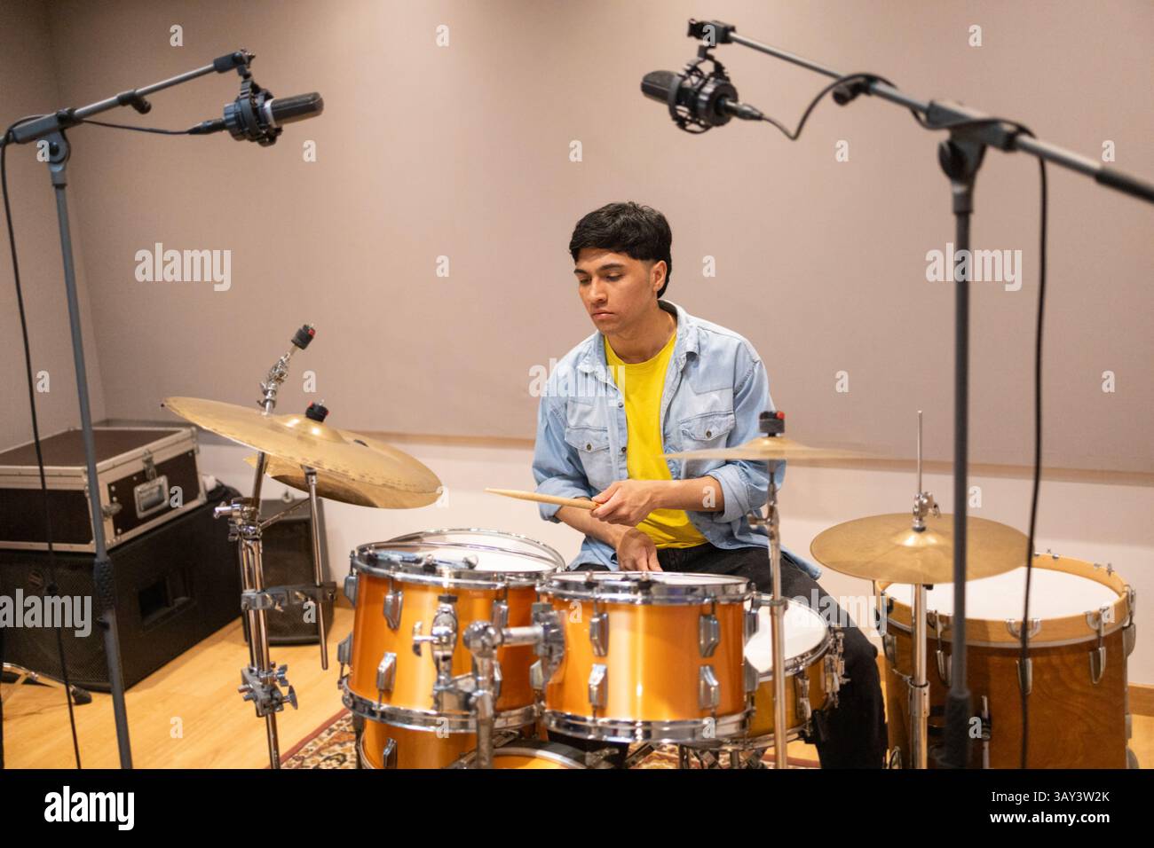 A drummer plays in a professional recording studio, surrounded by ...