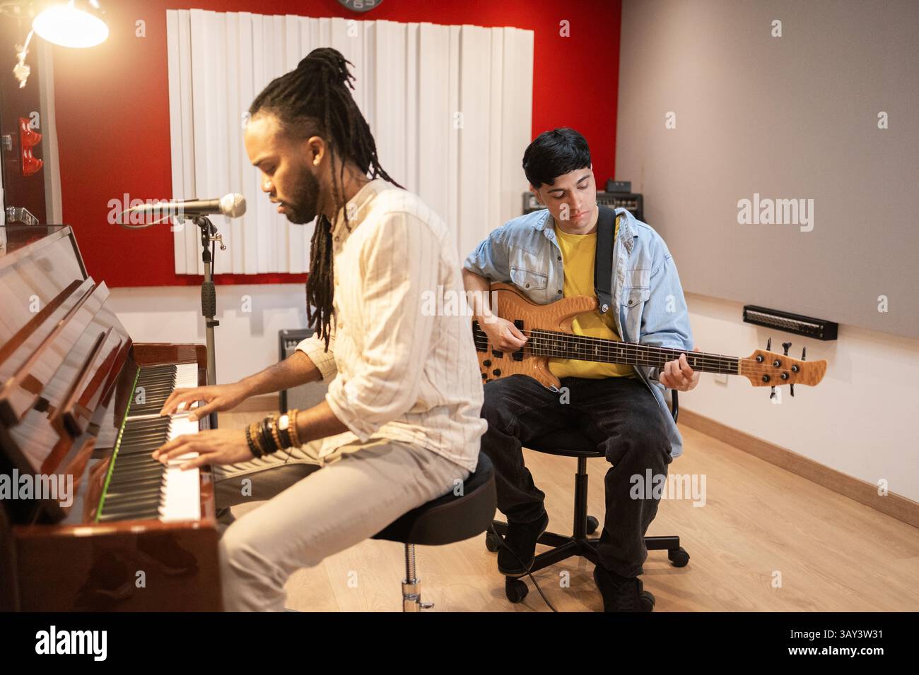 Two musicians collaborate in a professional recording studio, with one ...