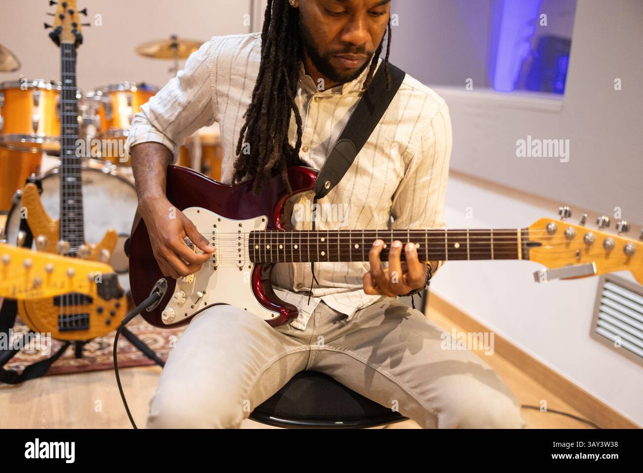 A black musician plays an electric guitar in a professional recording ...