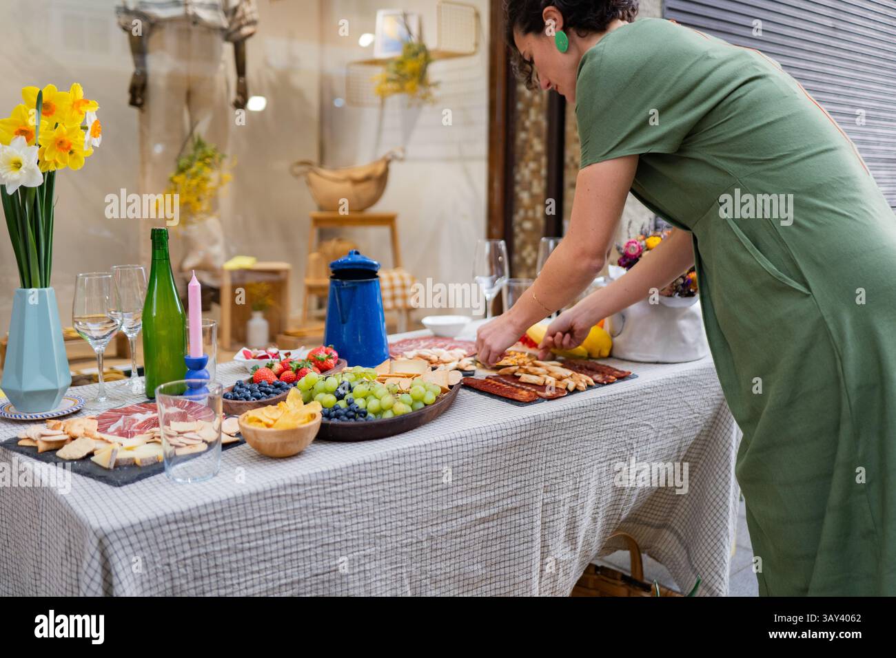 A woman in a green dress arranges a buffet table with an array of ...