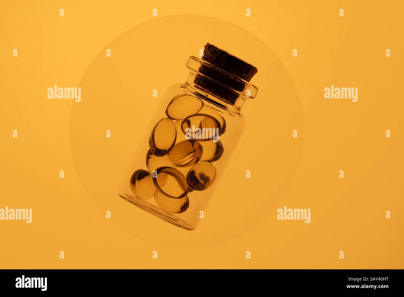 Transparent glass jar filled with shiny, colorful capsules of omega-3 ...