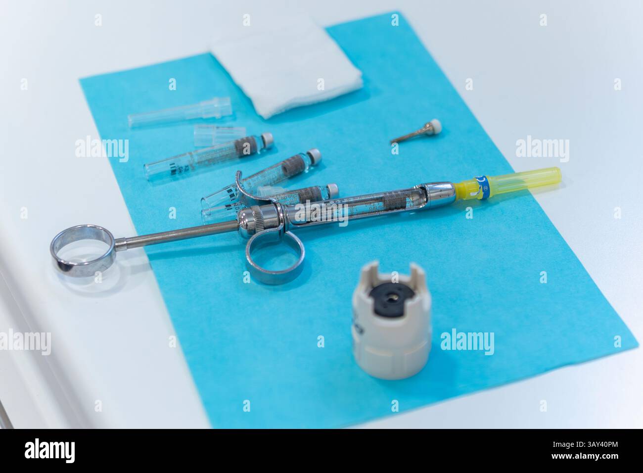 Dental anesthesia syringe and related tools on a blue sterile surface ...