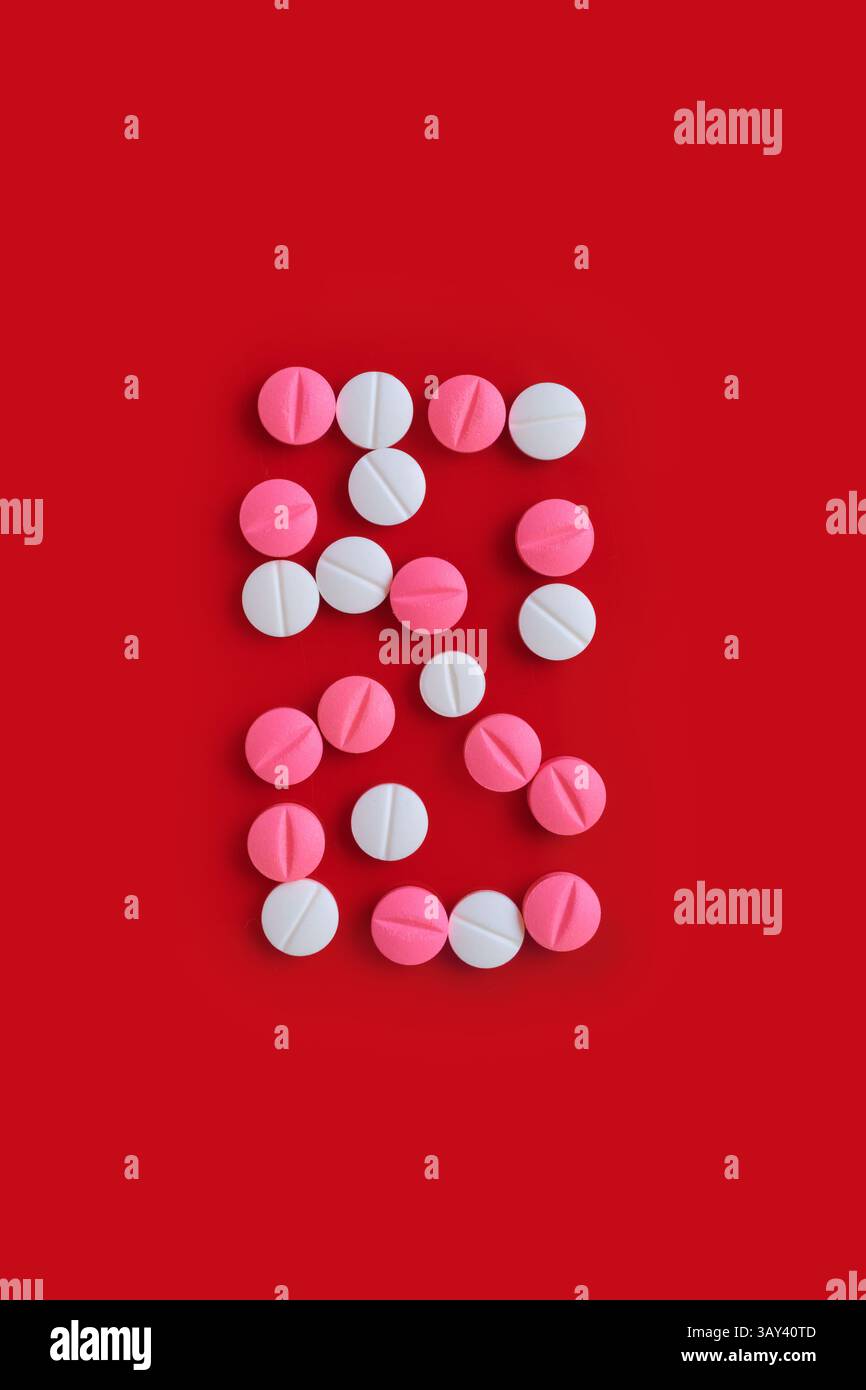 A creative arrangement of pink and white medical pills displayed on a ...