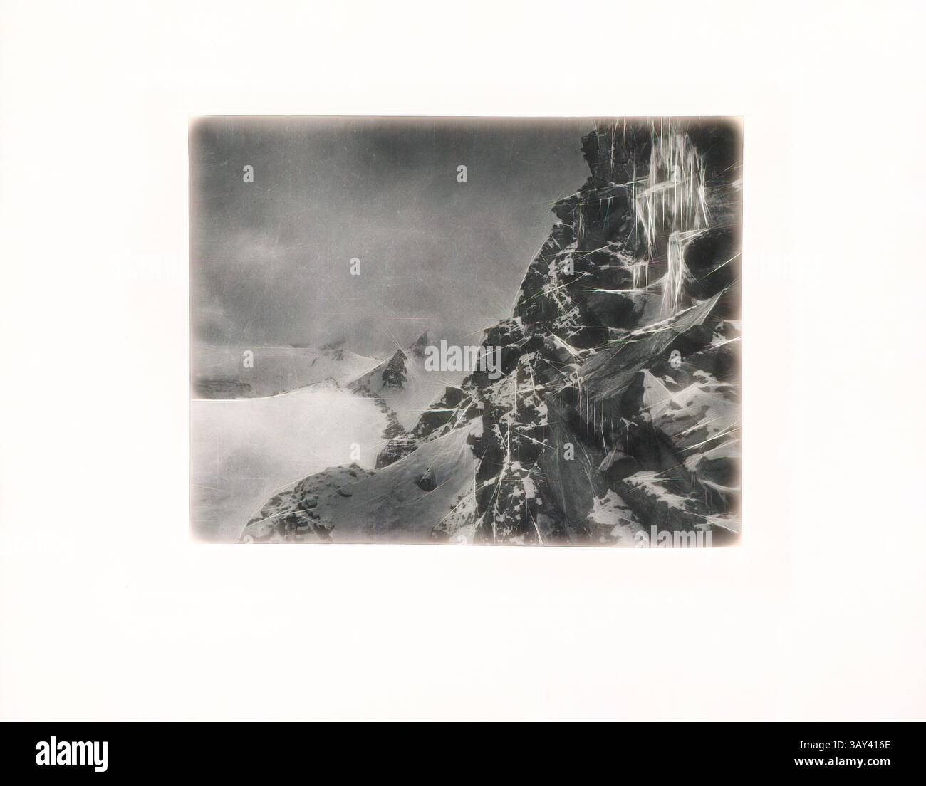 A dramatic landscape features rugged, icy cliffs towering over a vast ...