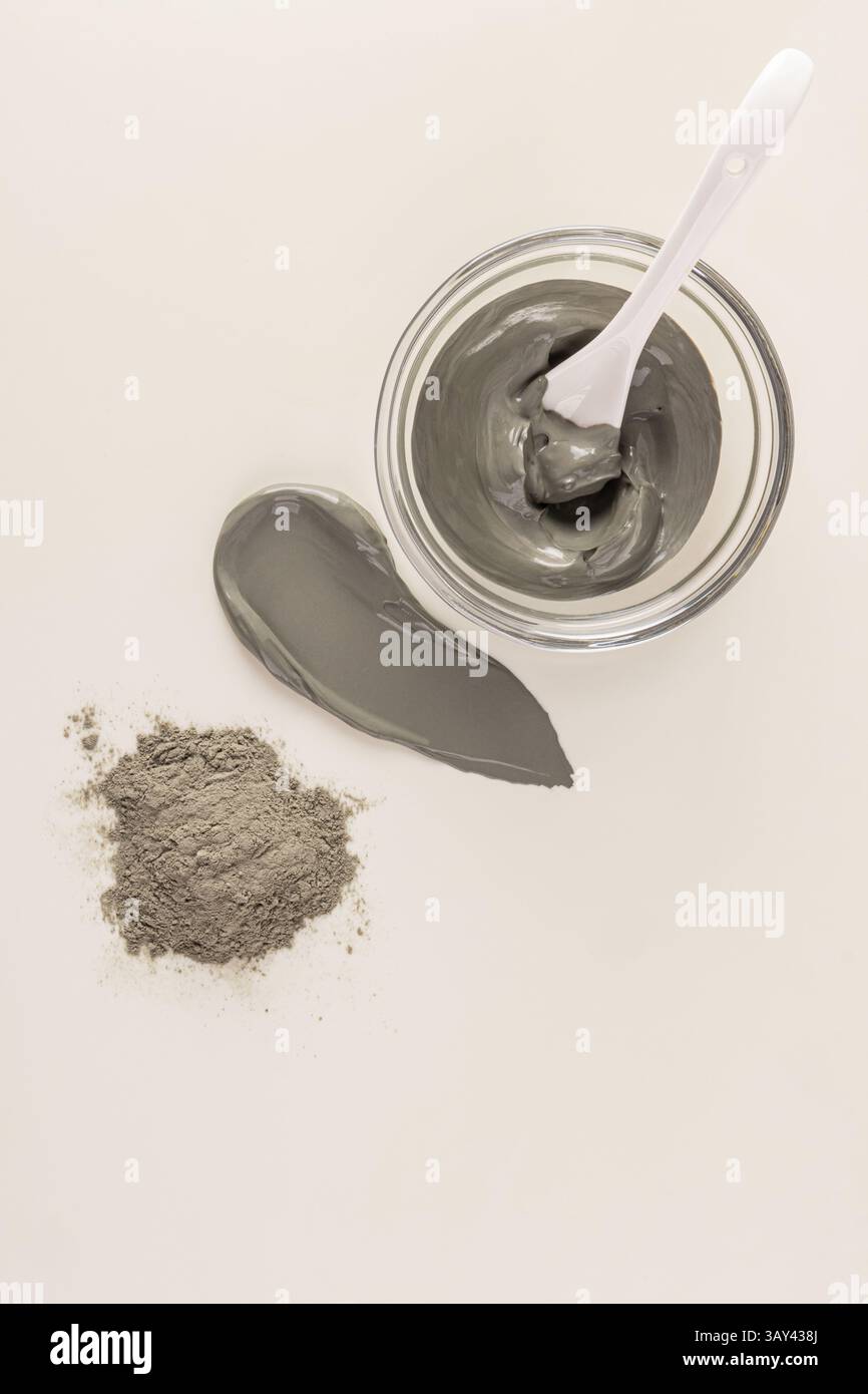 Top view of a glass bowl contains freshly mixed grey cosmetic clay mask ...