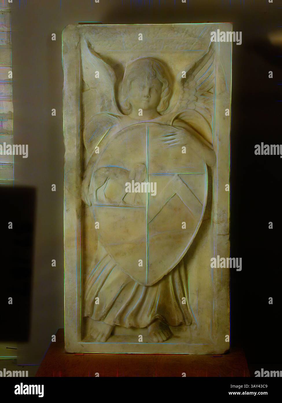 A carved relief of an angelic figure stands confidently, holding a ...