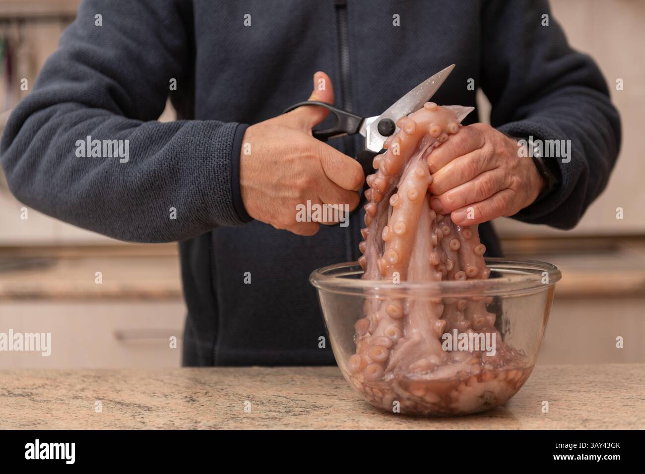A man uses scissors to cut an octopus, showcasing culinary skills in a ...