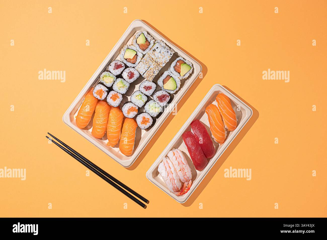 Top down view of assorted sushi in eco friendly trays, set against a ...