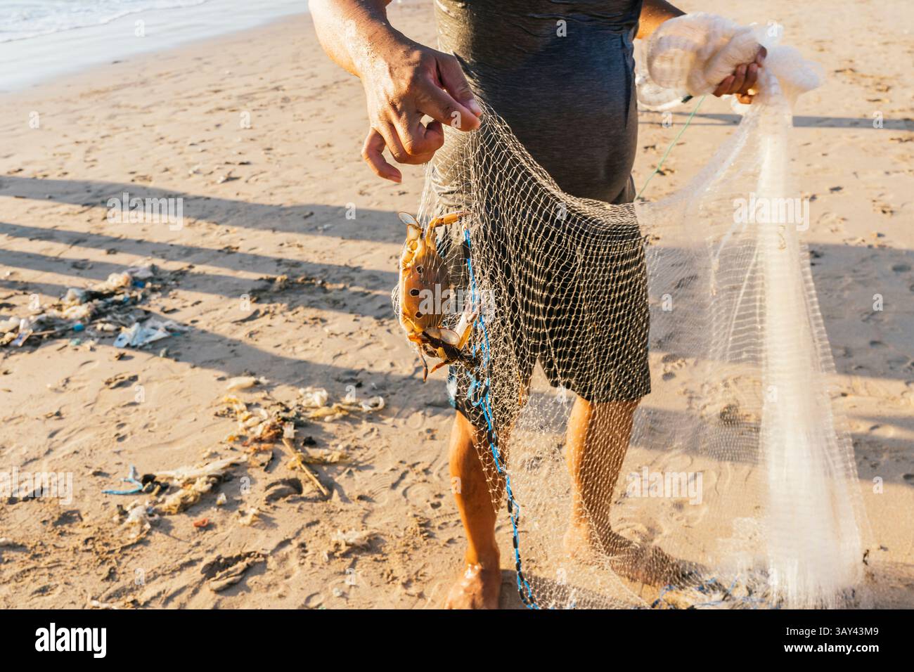 A fisherman holds a net with a crab, showcasing a fresh catch on a ...