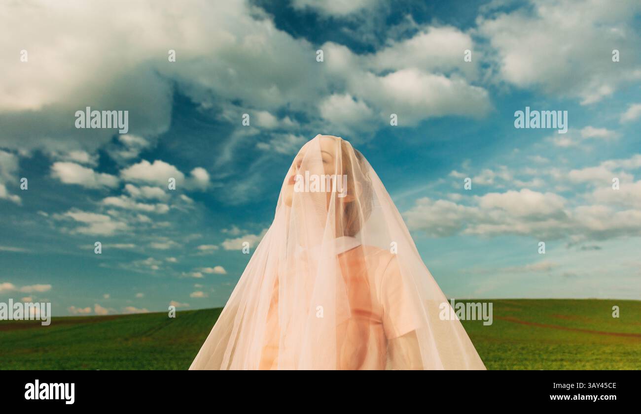 A woman stands outdoors, draped in sheer fabric, with a serene ...