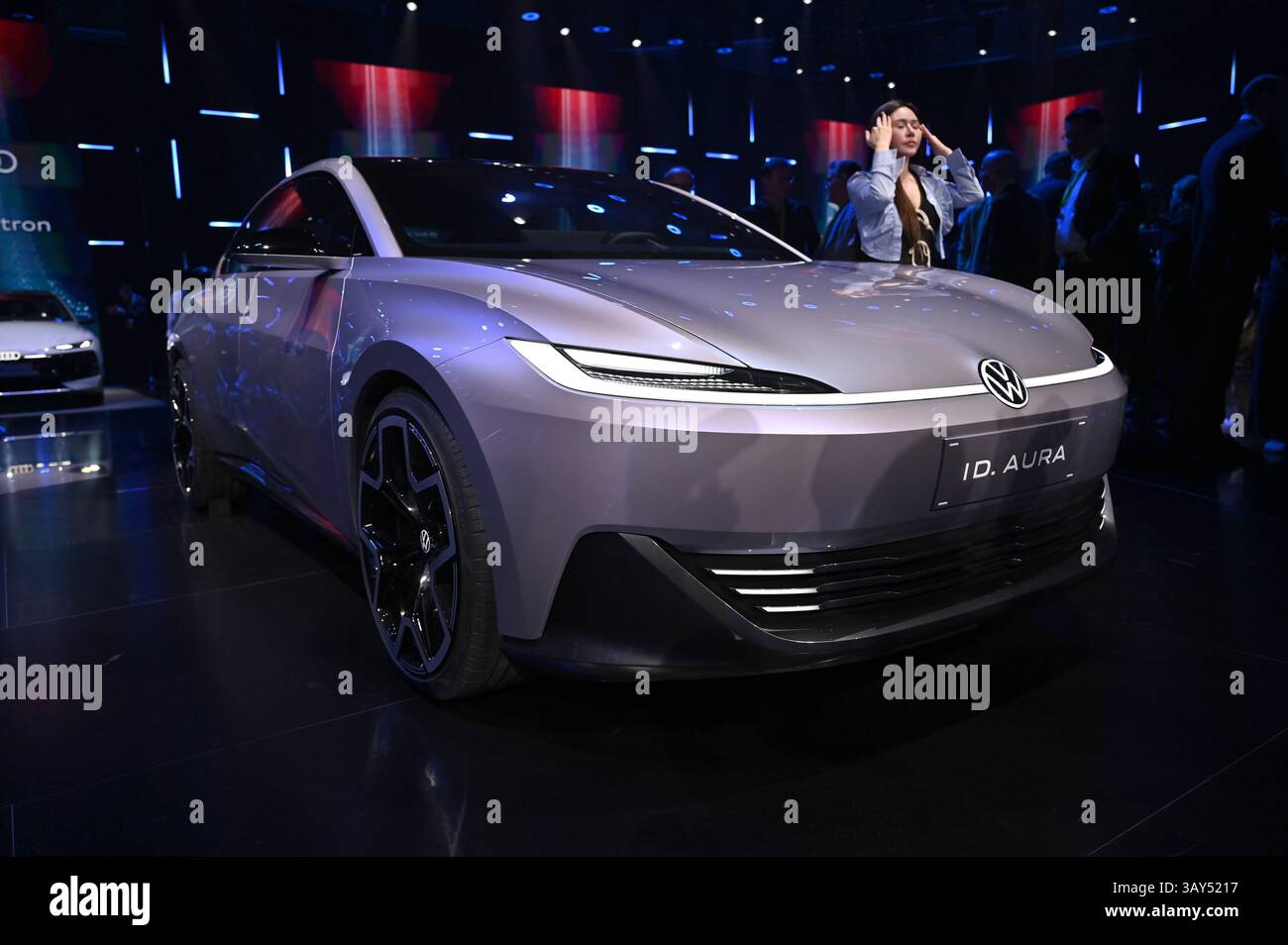 22 April 2025, China, Shanghai: A woman stands next to a VW ID.Aura - a ...