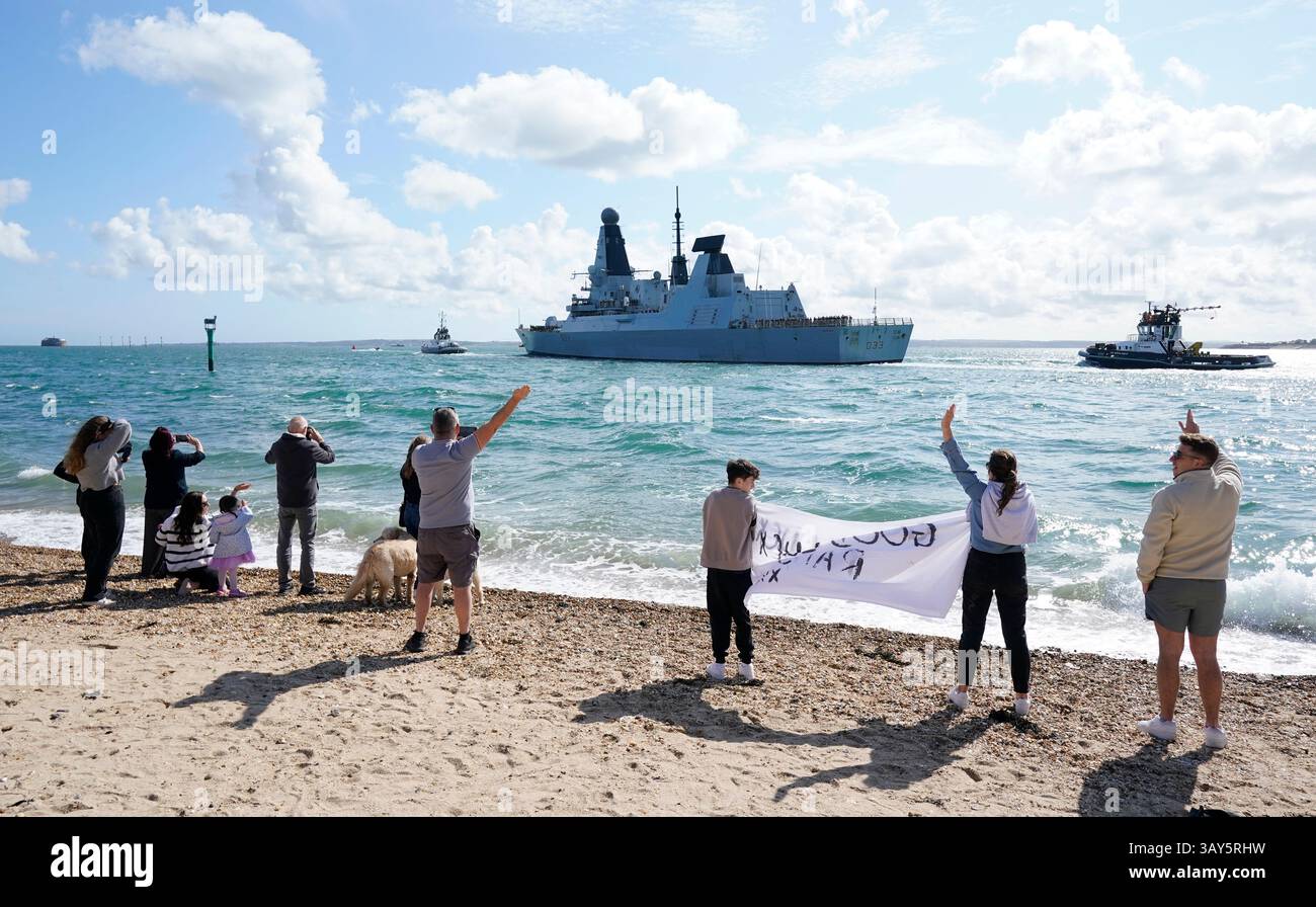 People wave from the beach towards the Royal Navy Type 45 Destroyer HMS ...
