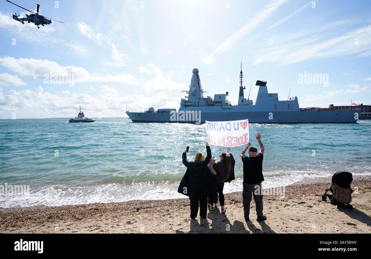People wave from the beach towards the Royal Navy Type 45 Destroyer HMS ...