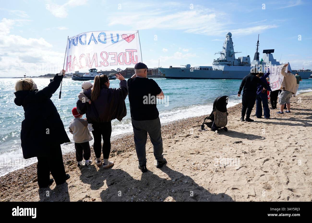 People wave from the beach towards the Royal Navy Type 45 Destroyer HMS ...