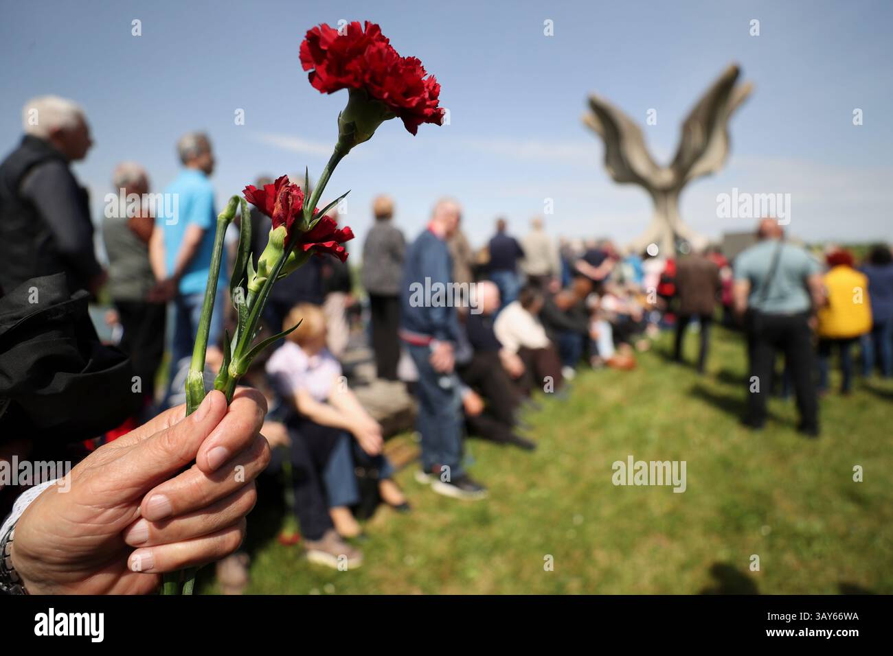 A person holds a flower as people gather around the monument ...