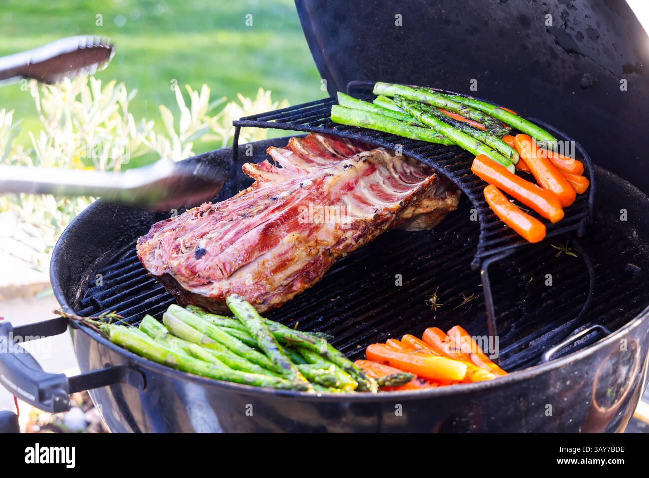 Barbecue zu Ostern. Lammrücken grillt auf einem Kugelgrill im Freien ...