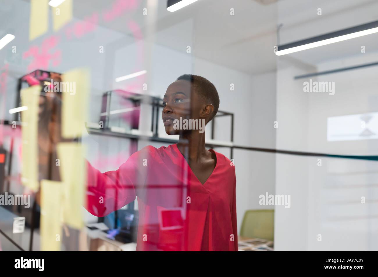 Young African American woman in red blouse placing bright sticky notes ...