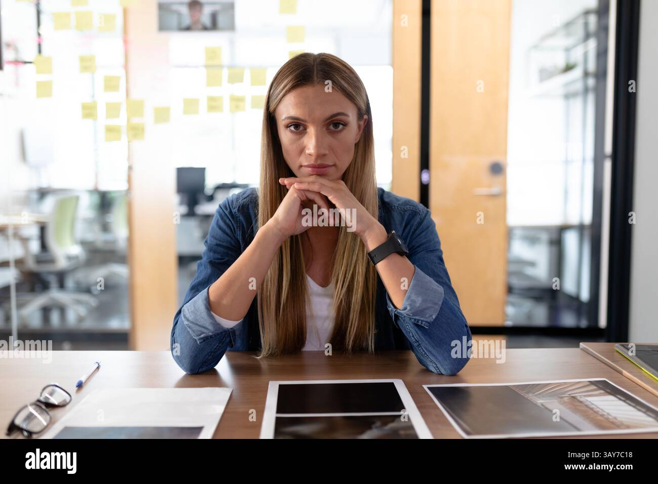 woman leaning forward at desk in modern office meeting room, using ...