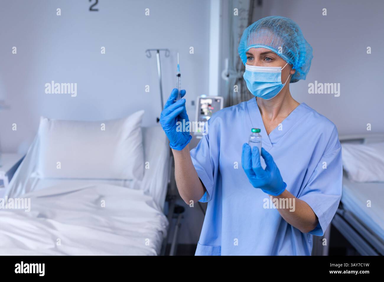Female nurse preparing injection with syringe and vial in hospital room ...