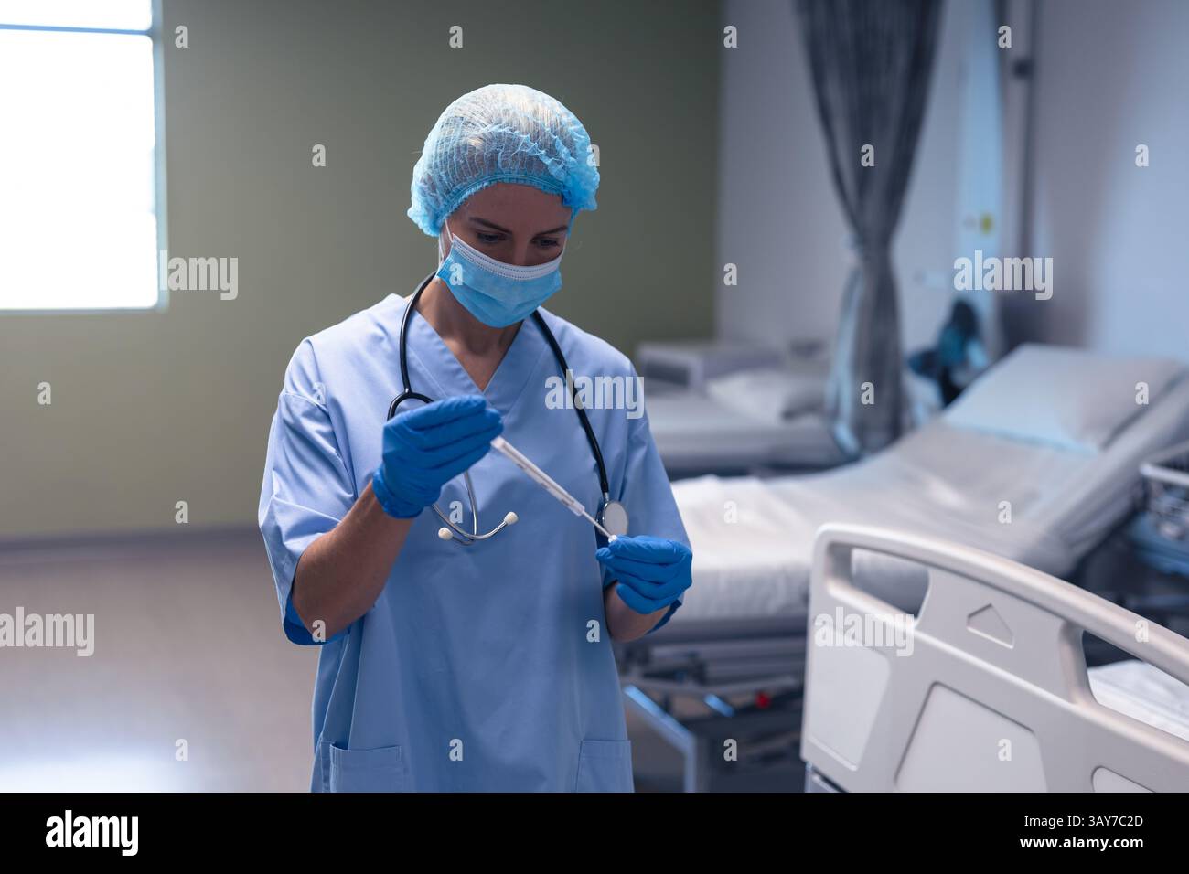 Female nurse drawing medication into syringe in hospital room, with ...