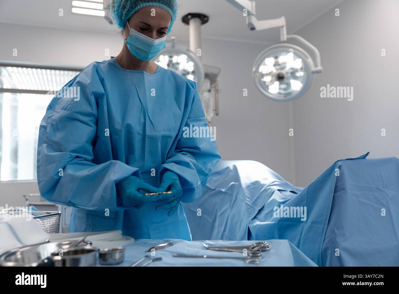 Female surgeon preparing instruments in operating room, using metal ...