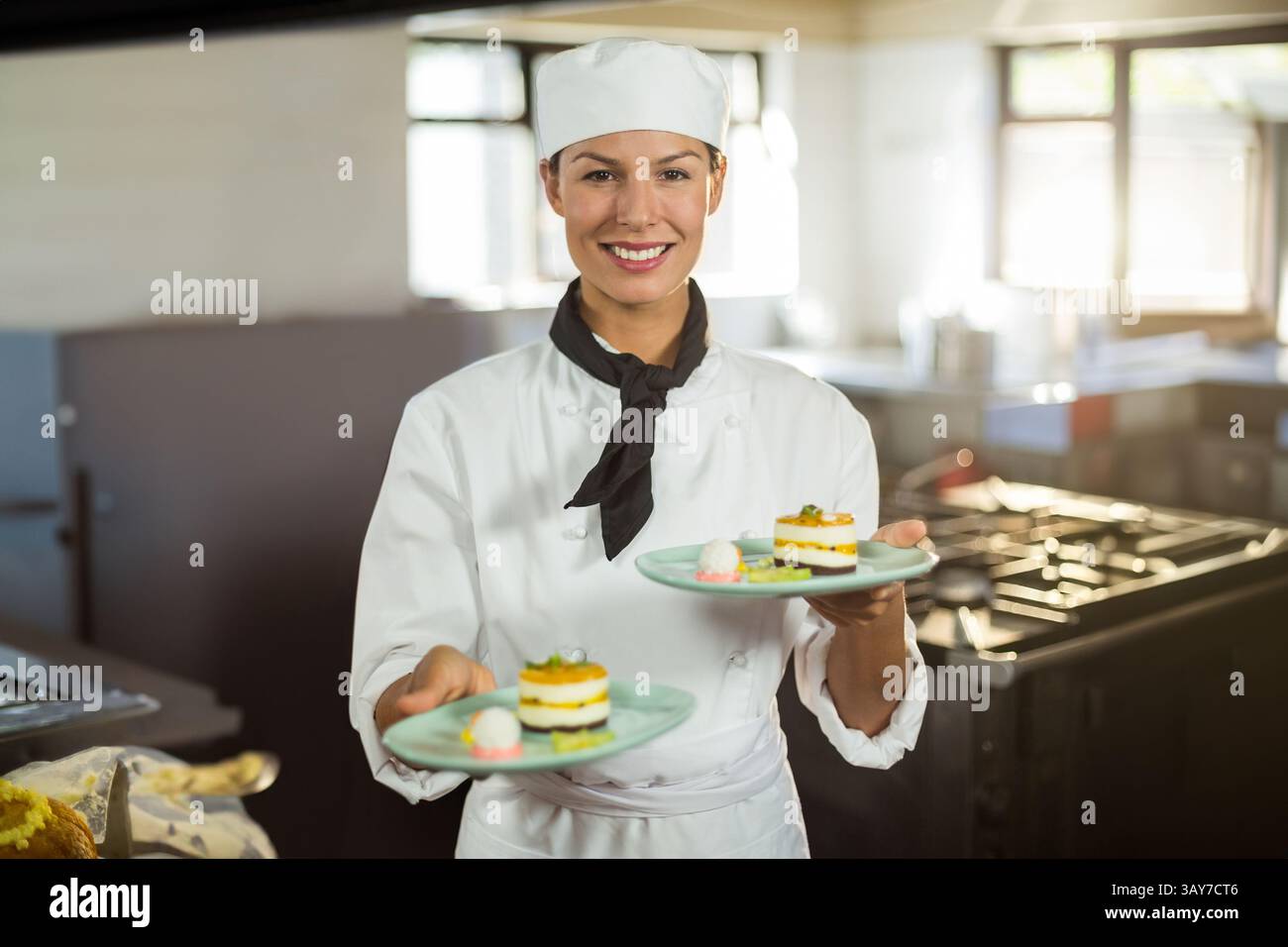 Portrait of chef presenting dessert plates in commercial kitchen Stock ...