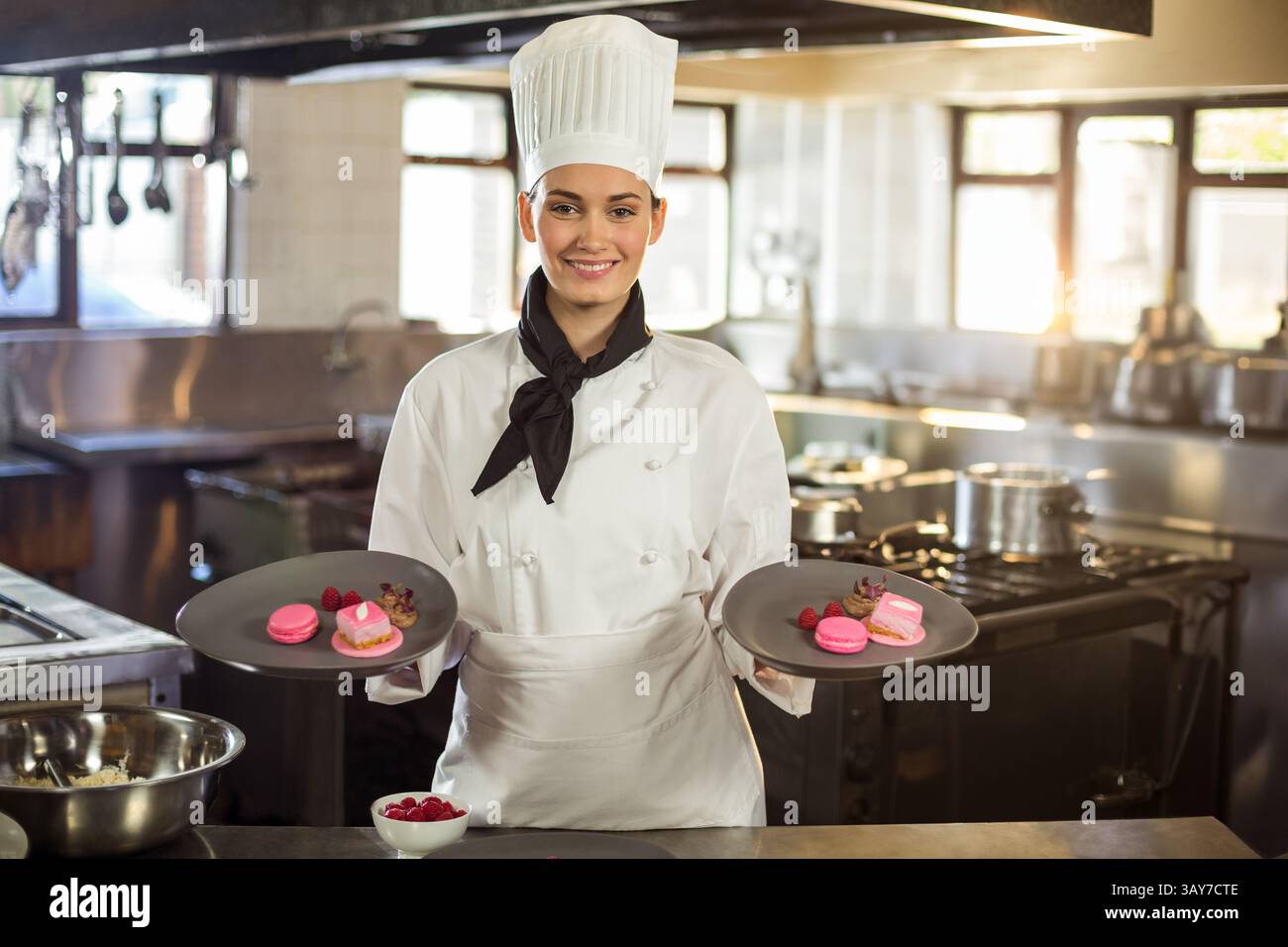 female chef standing at counter in professional kitchen, holding black ...