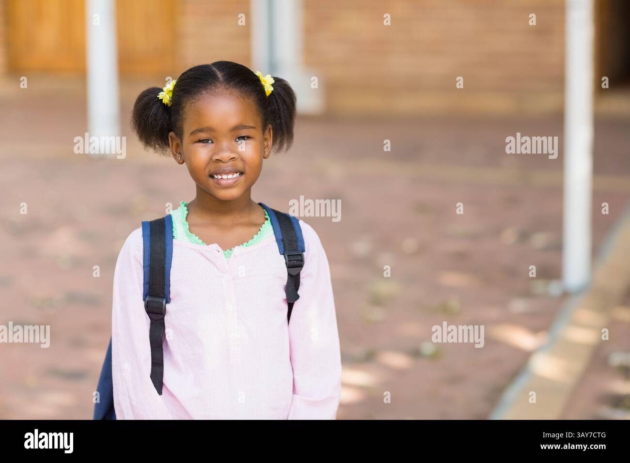 African American girl standing and smiling in brick school courtyard ...