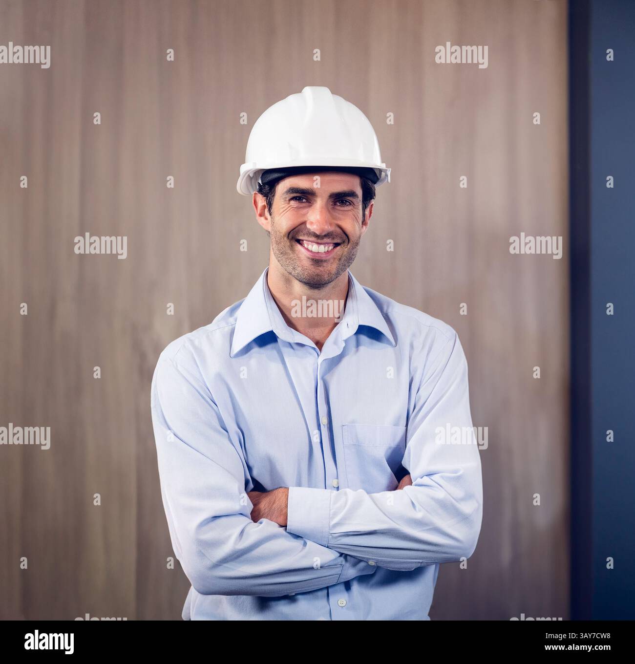Man standing in site office wearing white hard hat and light blue shirt ...
