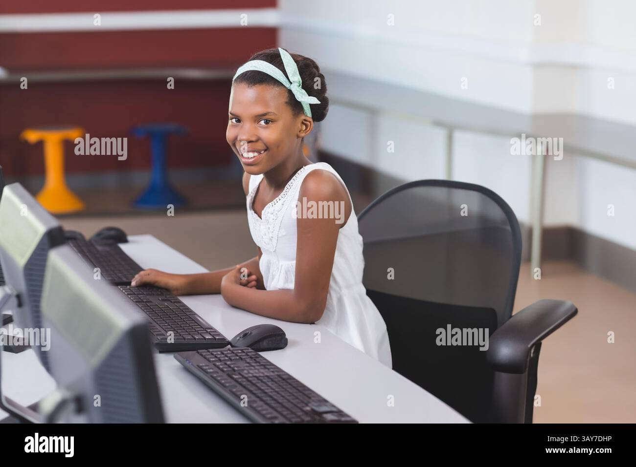 African American child sitting at white desk in bright computer lab ...